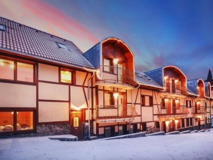 Uma fileira de edifícios em estilo chalé tradicional, com fachadas de madeira e telhados inclinados, emoldurada por uma paisagem nevada.