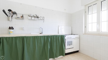 Uma cozinha com fogão branco, pia e janela.