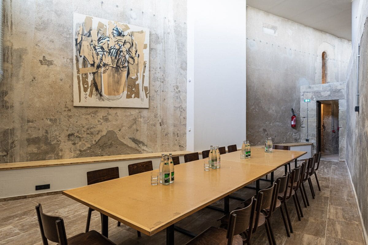 Uma sala de conferência com uma mesa comprida, cadeiras e um quadro na parede.