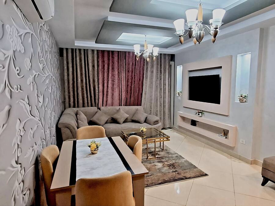 Uma sala de estar moderna com sofá, televisão, mesa de jantar e painéis decorativos na parede.