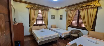 Quarto com duas camas de solteiro, uma cadeira, uma mesa pequena e um armário.