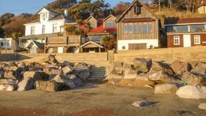 Um imóvel à beira-mar com vários edifícios, incluindo uma casa de madeira e um prédio branco com varanda.