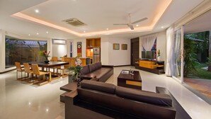 Uma sala de estar moderna com sofá, mesa de centro, televisão e área de jantar.