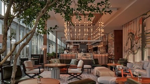 Um interior moderno com área de bar, assentos e uma grande janela que oferece luz natural.