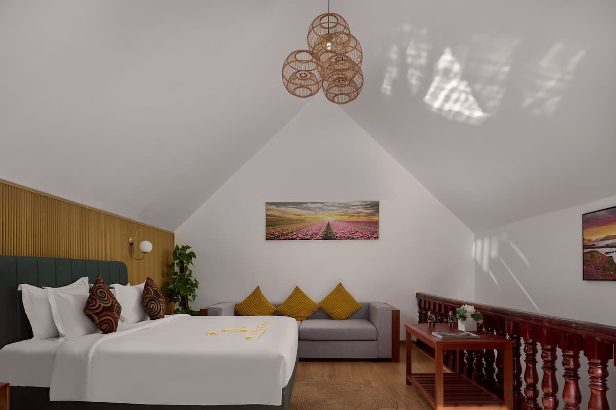 Quarto com cama, sofá, cabeceira de madeira, quadro na parede e corrimão de escada.