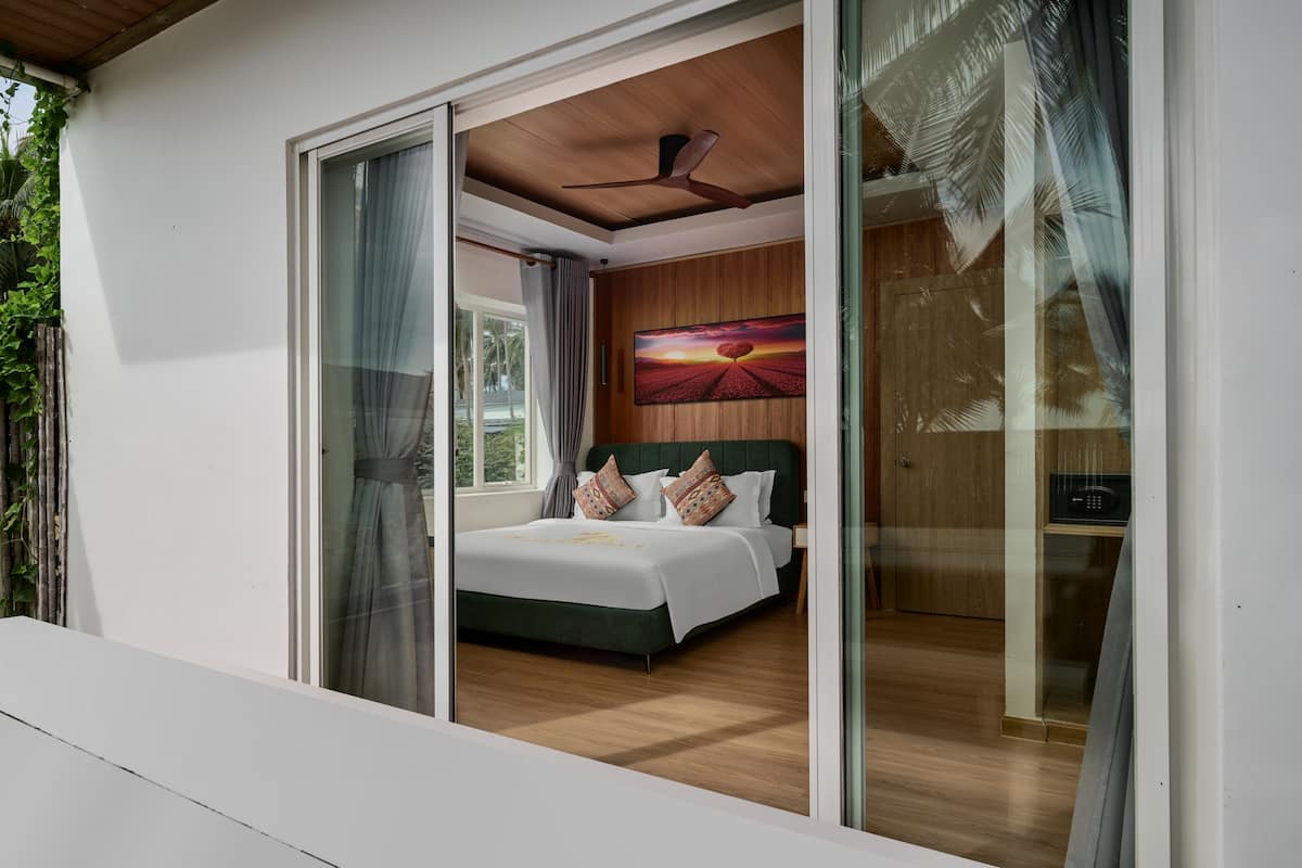 Quarto com cama, ventilador de teto, um quadro e uma porta de correr de vidro.