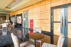 Um hall com uma mesa redonda e cadeiras, um hidrante vermelho e uma parede com padrão decorativo.