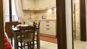 Cozinha moderna com armários brancos, painel de azulejos e um espaço de refeições com mesa e cadeiras.