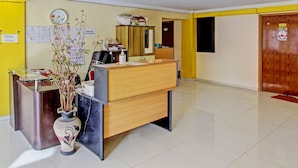 Uma área de recepção com uma mesa de madeira, um vaso com flores, um relógio e uma porta com a inscrição "101".
