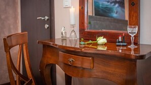 Uma escrivaninha de madeira com um espelho, uma vela, um vaso e um copo de água.