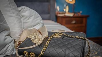 Cama com uma bolsa de mão preta acolchoada, com alça de corrente dourada e um broche decorativo.