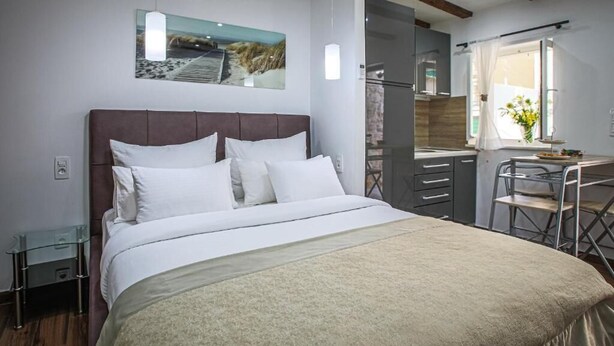 Quarto com uma cama grande, mesa de cabeceira, espelho e janela com cortinas.
