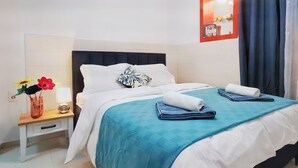 Quarto de hotel com cama, mesa de cabeceira, um vaso com flores e um espelho.