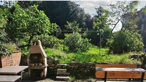 Um pátio com uma churrasqueira de pedra, um banco de madeira e uma mesa.