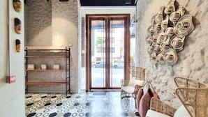 Decoração moderna com piso padronado em hexágonos, móveis de vime e um objeto decorativo fixado na parede.