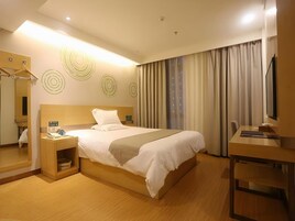 Quarto de hotel com uma cama grande, mesa de cabeceira e escrivaninha com cadeira.