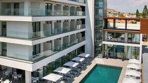 Um hotel moderno com piscina no terraço, várias varandas e áreas de estar ao ar livre.