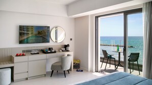 Quarto de hotel moderno com varanda, cama, escrivaninha e vista para o mar.