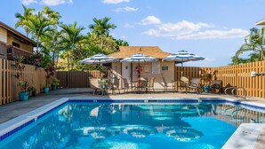 Piscina com deck de madeira, espreguiçadeiras e guarda-sóis.