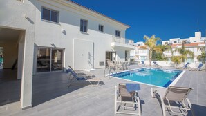 Área de piscina com espreguiçadeiras e céu azul.