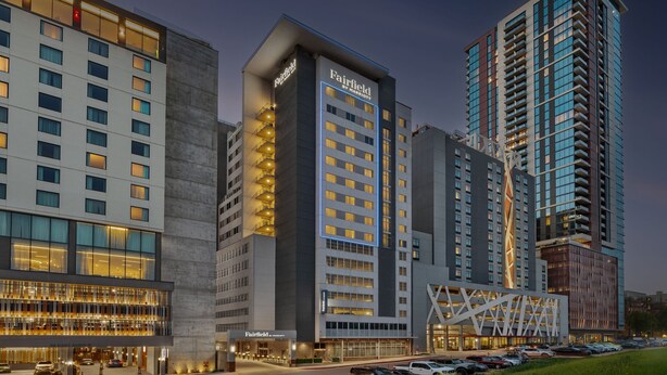 Um hotel de vários andares com design moderno, exibindo uma placa chamativa com a inscrição "Fairfield" na fachada.