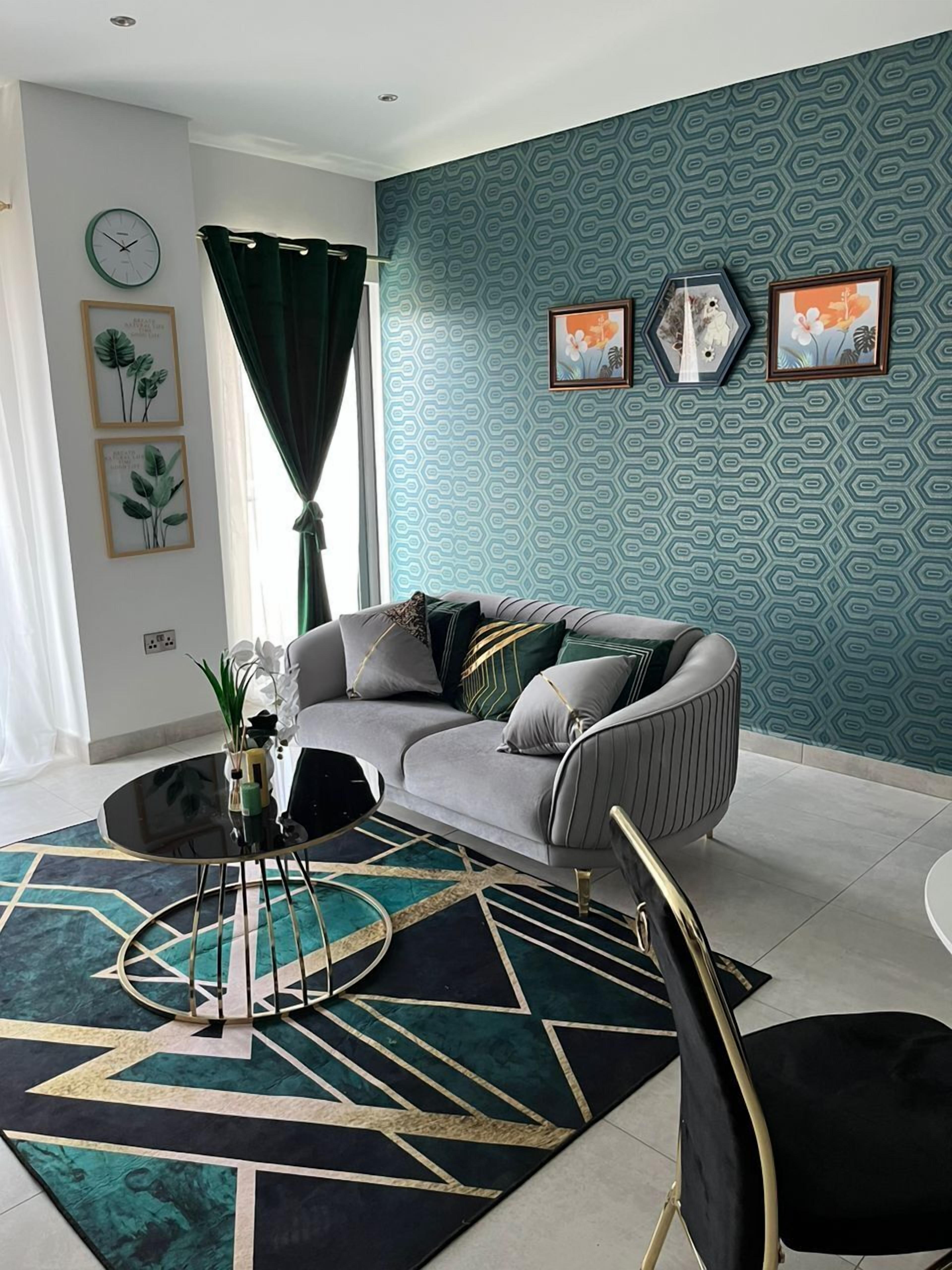 Uma sala de estar moderna com um sofá cinzento, uma mesa de centro preta e um tapete estampado.