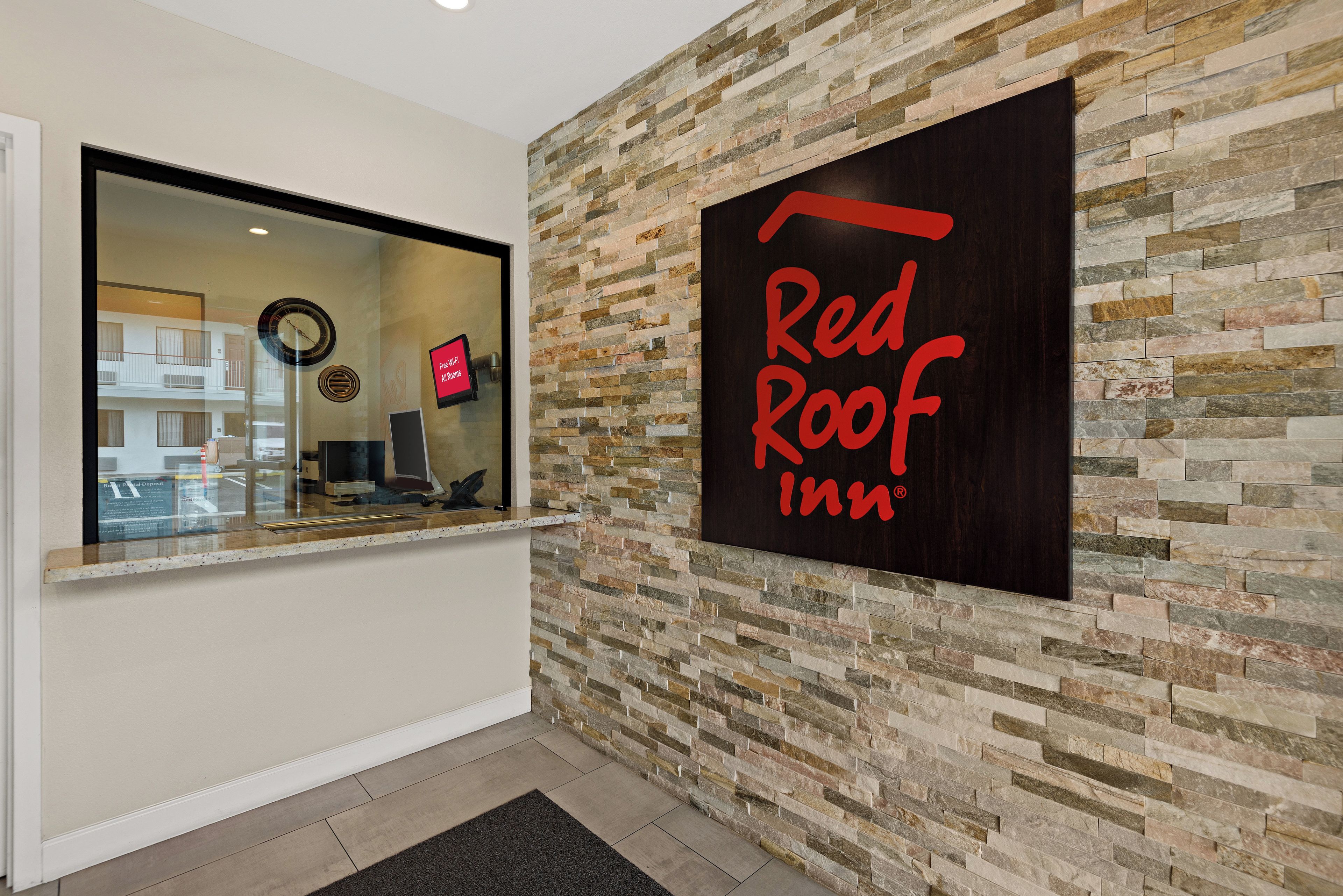 Uma área de recepção com parede de pedra e placa da Red Roof Inn.