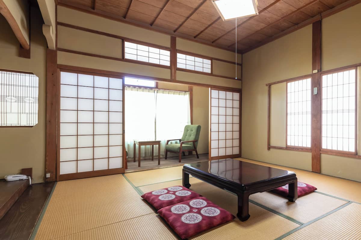 Um quarto japonês tradicional com tatames, painéis shoji e uma mesa baixa.