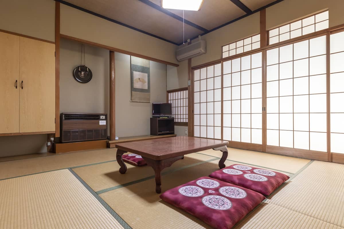 Um quarto japonês tradicional com tatames, uma mesa de madeira baixa e biombos shoji.
