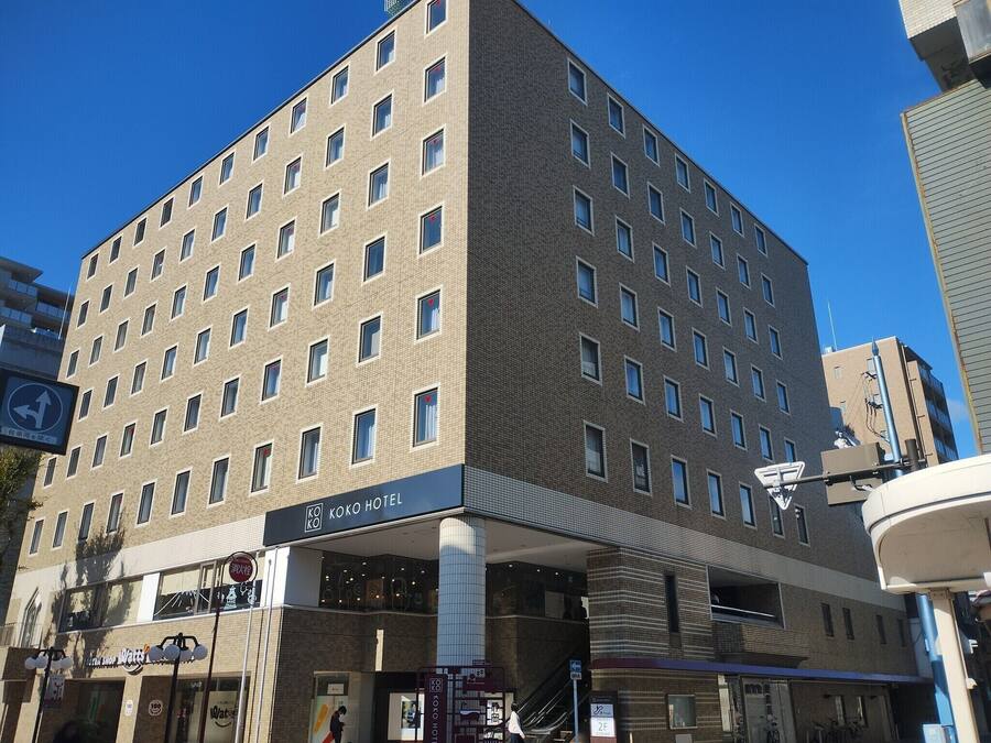 Um hotel de vários andares com fachada de tijolos moderna, uma entrada visível e uma placa indicando ser um Koko Hotel.