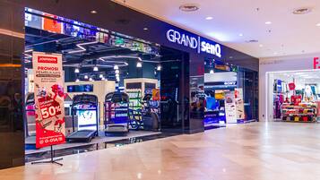 Um centro comercial com uma loja GRAND SENQ que exibe esteiras e outros equipamentos de ginástica.