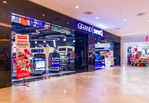 Um centro comercial com uma loja GRAND SENQ que exibe esteiras e outros equipamentos de ginástica.