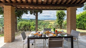 Uma área de refeições ao ar livre com uma mesa posta para o café da manhã, com vista para uma paisagem deslumbrante.