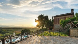 Um caminho de pedra leva a uma piscina com vista para uma paisagem rural e um edifício com telhado de azulejos.