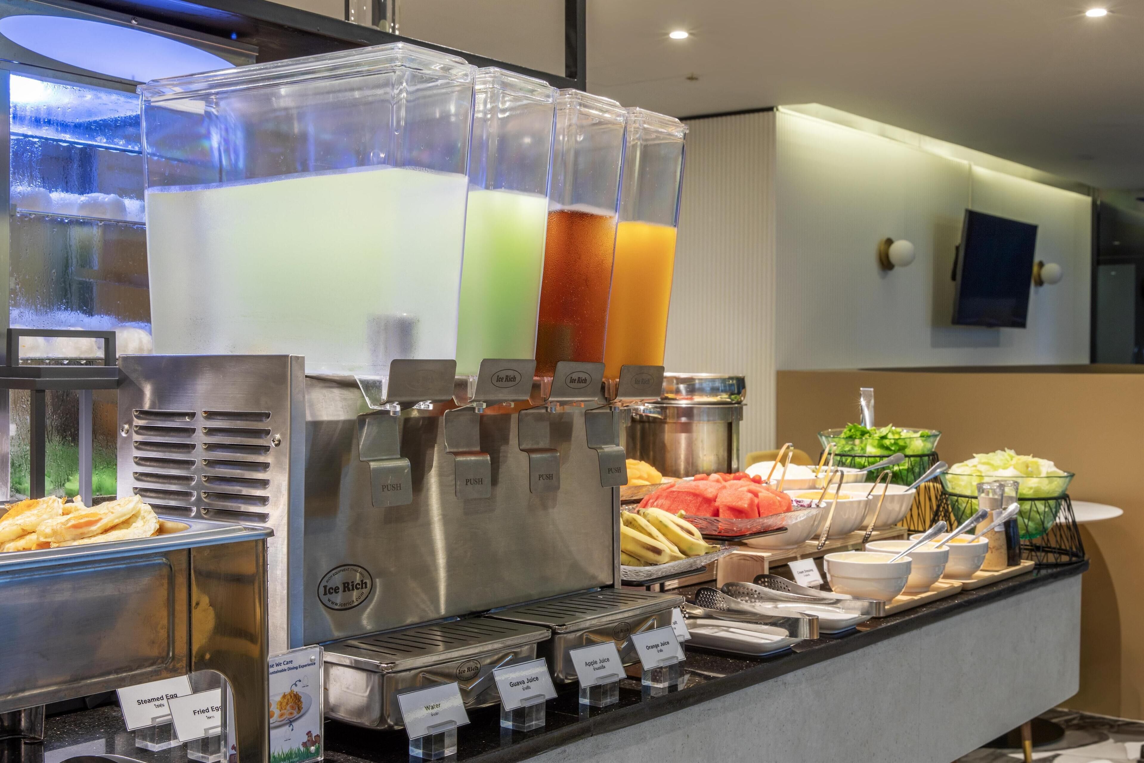 Buffet com diversas opções de comida, incluindo ovos cozidos no vapor, ovos fritos e uma seleção de frutas e vegetais.