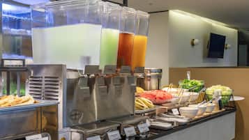 Buffet com diversas opções de comida, incluindo ovos cozidos no vapor, ovos fritos e uma seleção de frutas e vegetais.