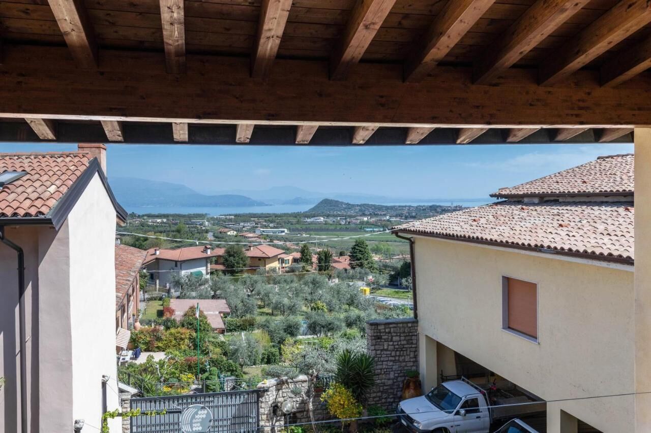 Vista de uma varanda com vista para uma área residencial, com casas, árvores e montanhas ao longe.