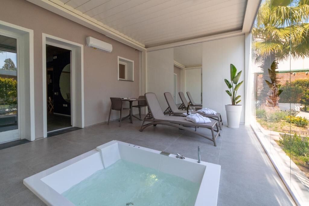 Uma área de spa com uma banheira grande, cadeiras de descanso e uma planta em vaso.