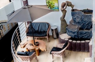 Uma área de estar ao ar livre circular com um banco acolchoado, uma mesa com um tambor e uma estrutura de pedra decorativa.