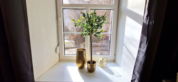 Uma janela com uma planta e dois vasos decorativos no parapeito.