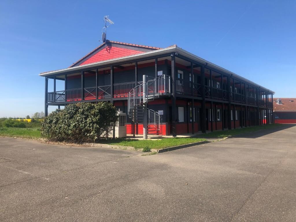 Um edifício de dois andares com varandas, telhado vermelho e céu claro.