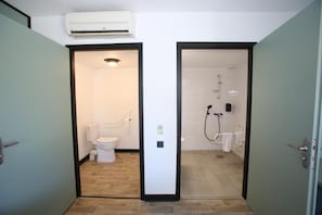 Uma casa de banho com sanita, chuveiro e um porta-toalhas.