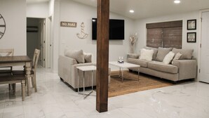 Uma sala de estar moderna com sofá, mesa de centro e área de jantar.
