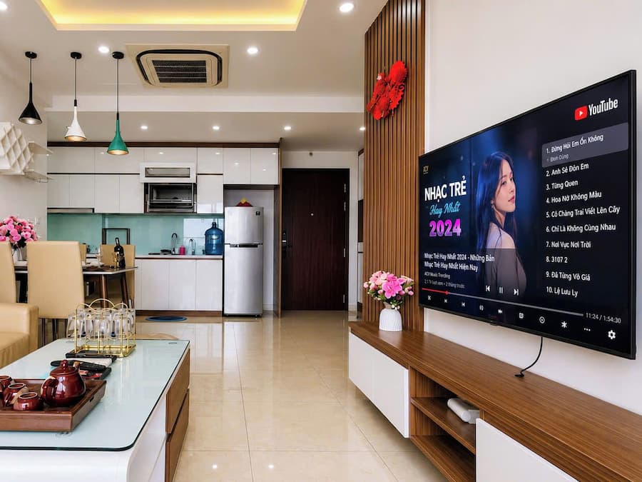 Uma sala de estar moderna com um sofá, mesa de centro e uma TV de tela plana exibindo um videoclipe.