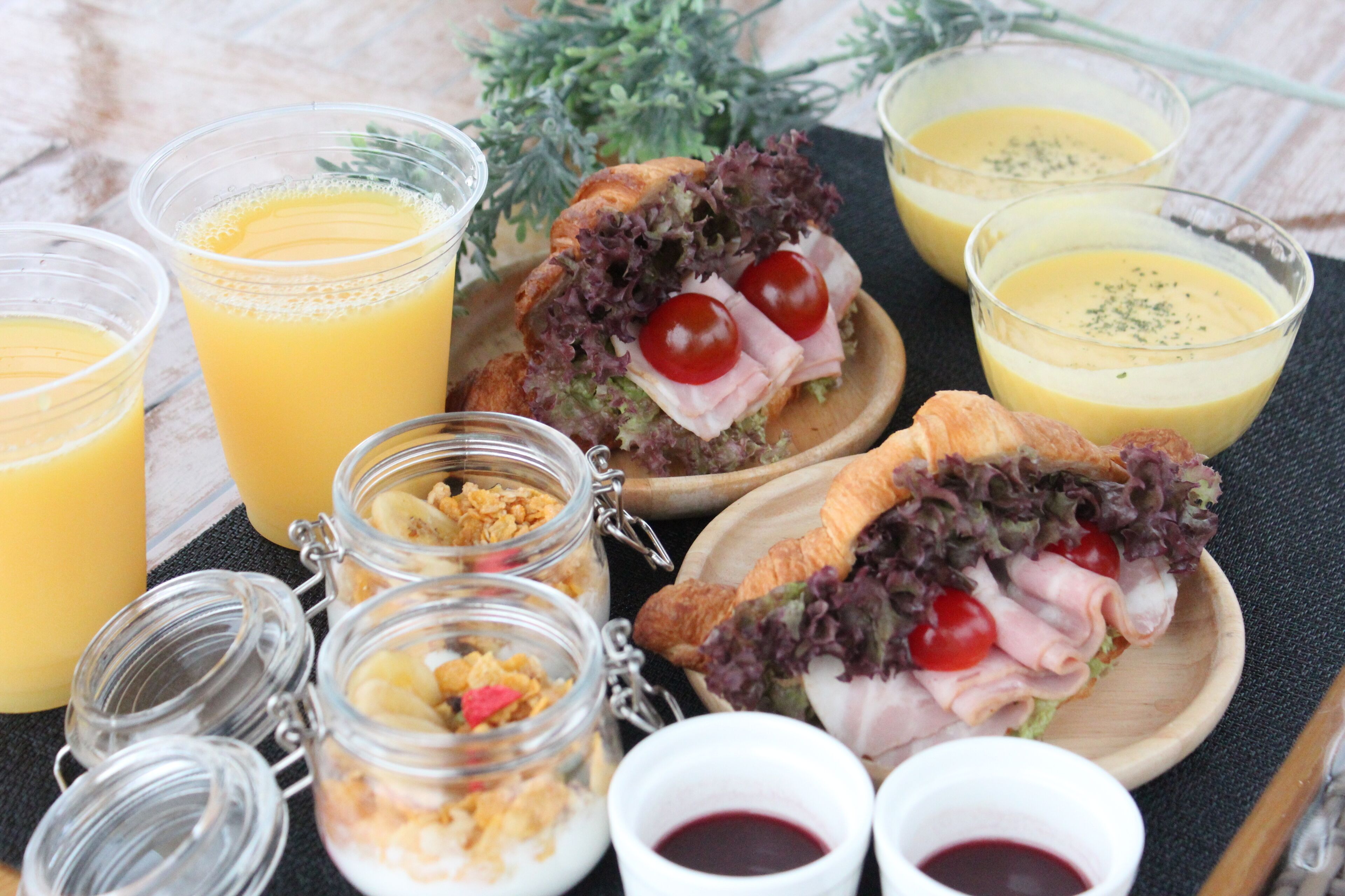 Mesa de café da manhã com sanduíches, frutas e bebidas.