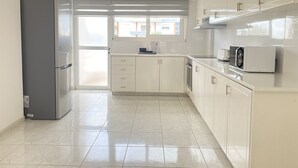 Uma cozinha moderna com armários brancos, uma geladeira cinza e um micro-ondas.
