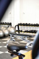 Uma academia com equipamentos de ginástica, incluindo halteres, bolas de medicina e um banco.