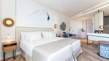 Quarto de hotel moderno com uma cama grande, mesas de cabeceira, escrivaninha, espelho e uma obra de arte na parede.