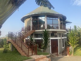 Um edifício de vários andares com uma seção circular central, uma escada com corrimão de metal e uma entrada com portão.