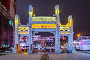 Um arco chinês tradicional com texto iluminado, provavelmente um ponto turístico ou entrada para uma área histórica.